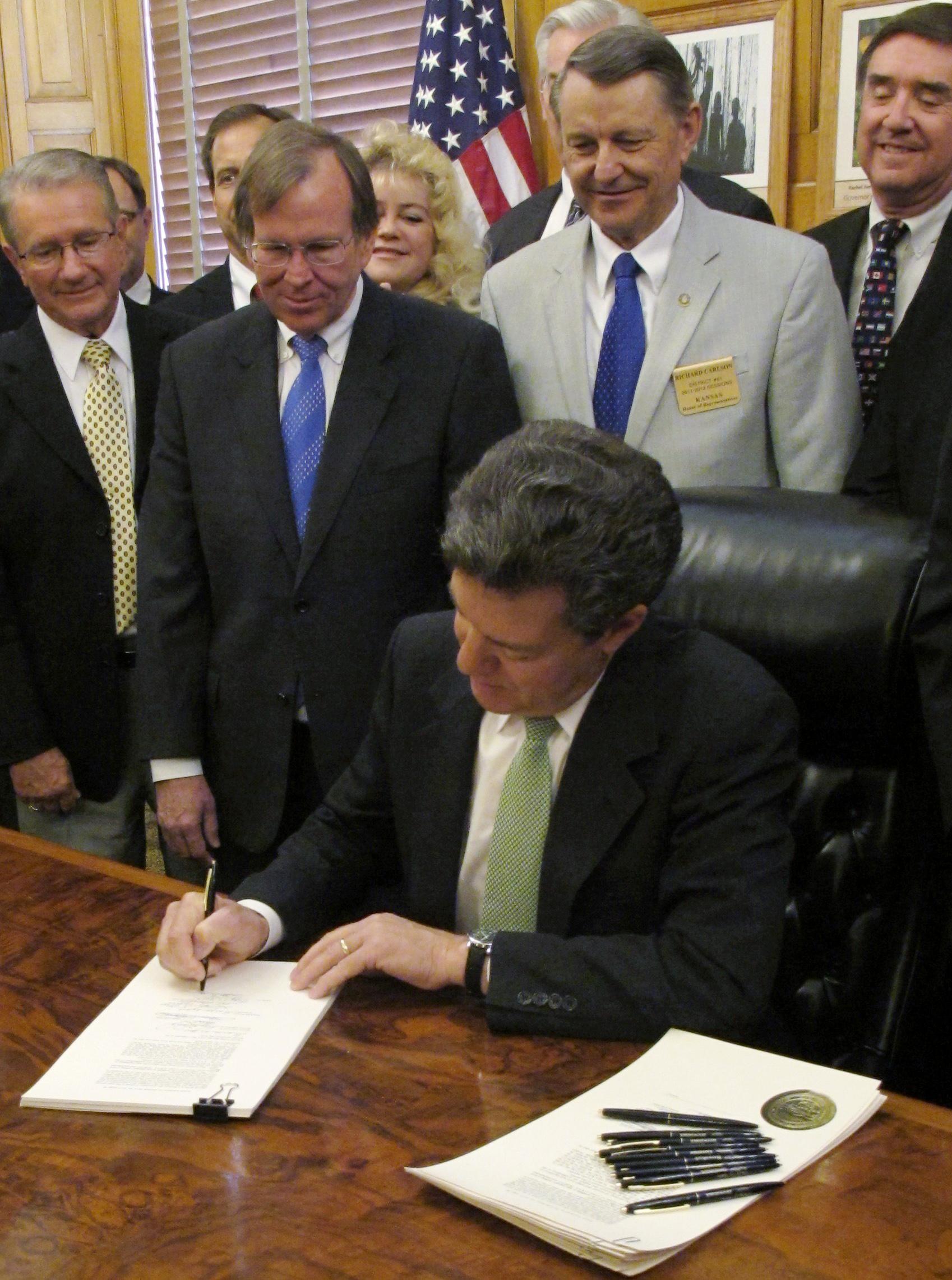 Kansas governor signs income tax cuts into law | AP News