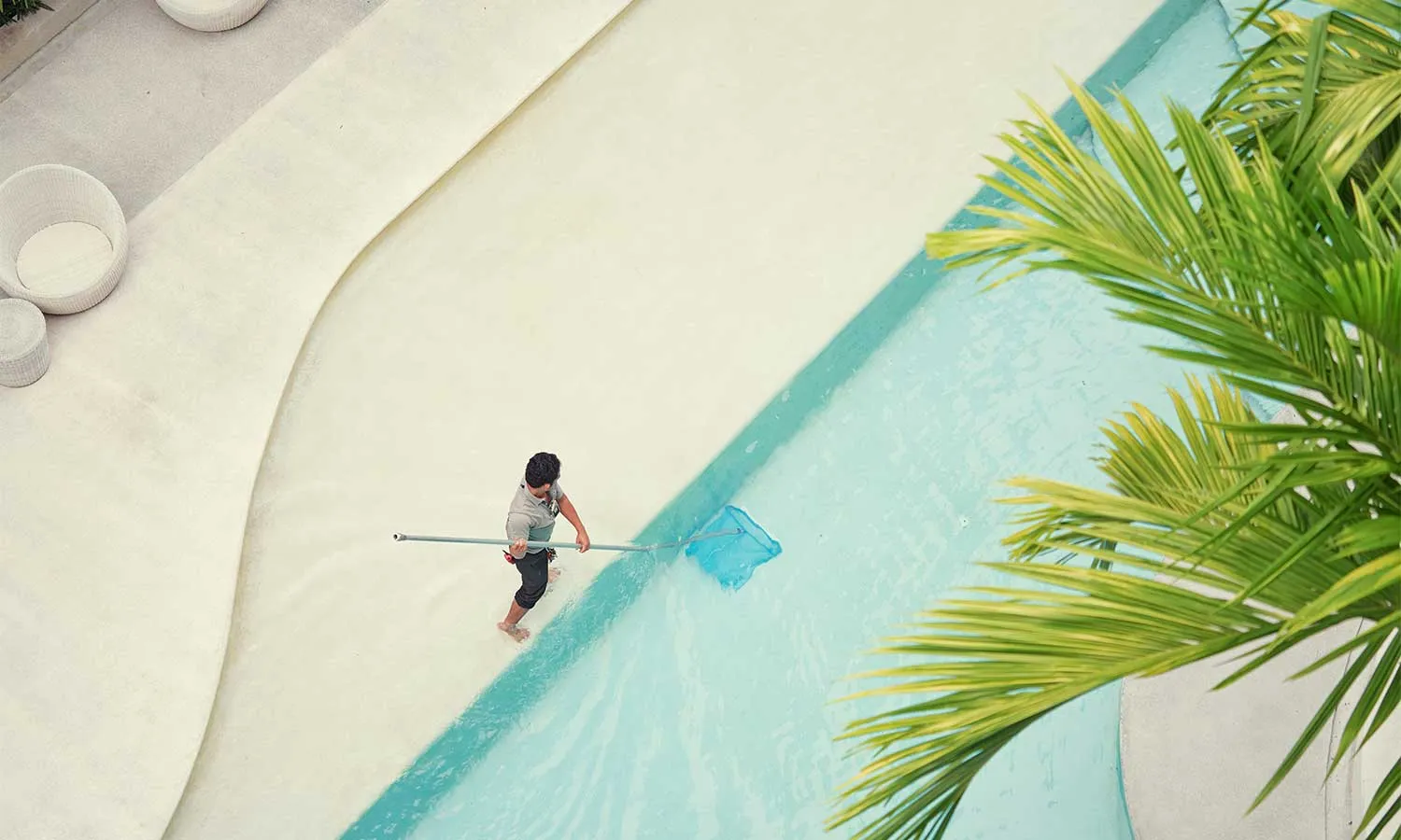 An overhead view of a person performing swimming pool cleaning with a ...